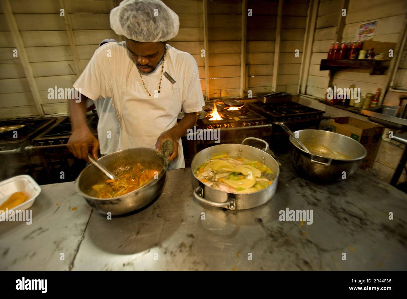 Cook stirs a pot in the kitchen of a restaurant in Jamaica; Alligator ...