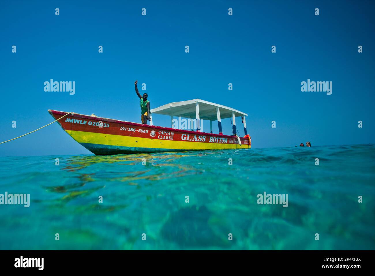 Tour guide waves from his glass bottomed tour boat in the Caribbean ...