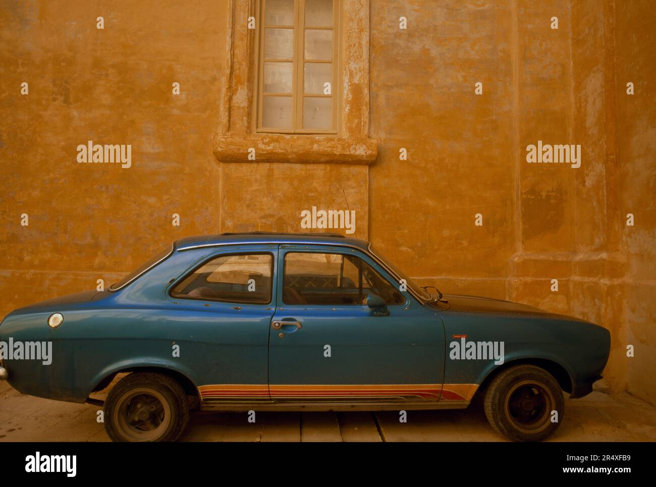 Vintage blue sports car parked along a weathered wall; Mdina, Malta ...