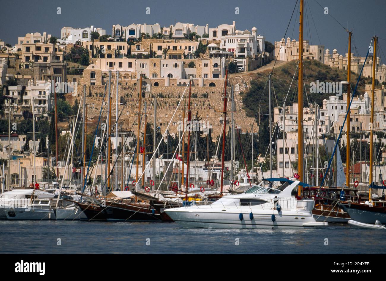 Boats docked in Bodrum harbor with houses on a hill in the background ...