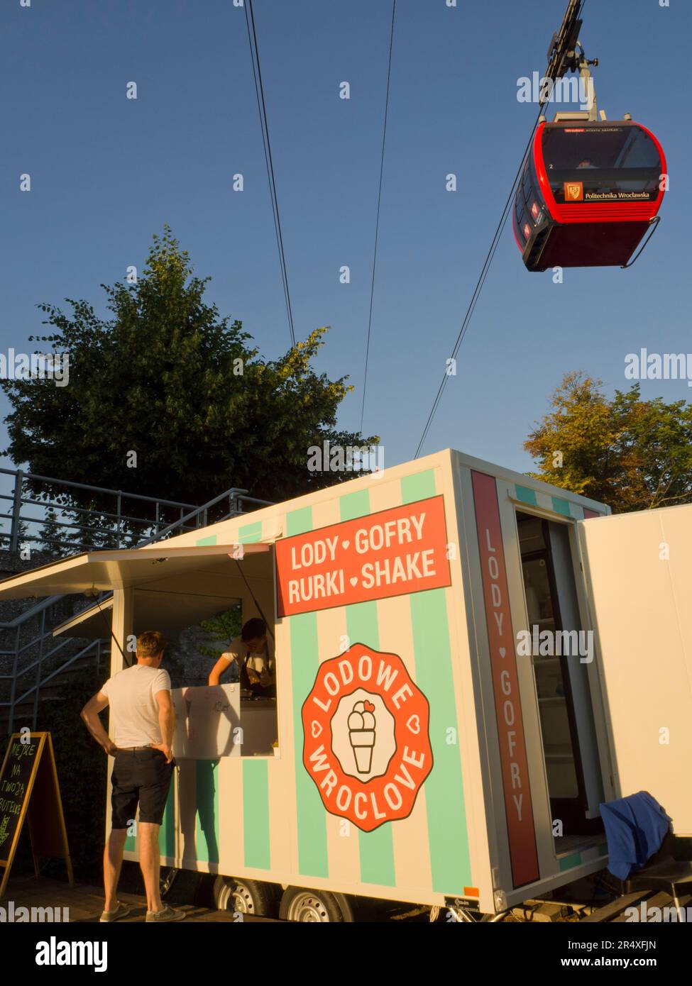 Ice cream seller in mobile kiosk serving a customer and cable car ...