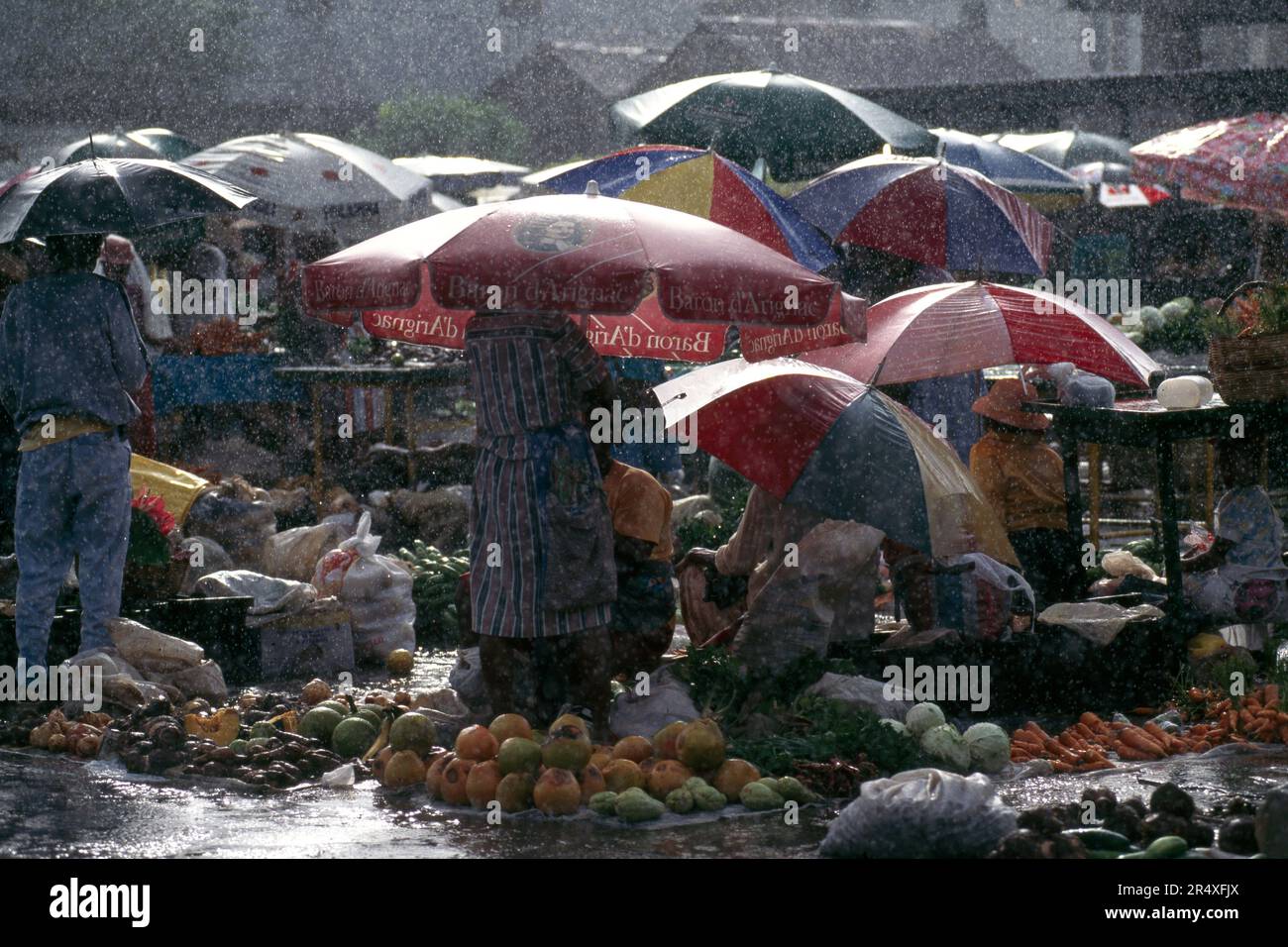 Shoppers in an open air market in a heavy rainfall; Commonwealth of ...