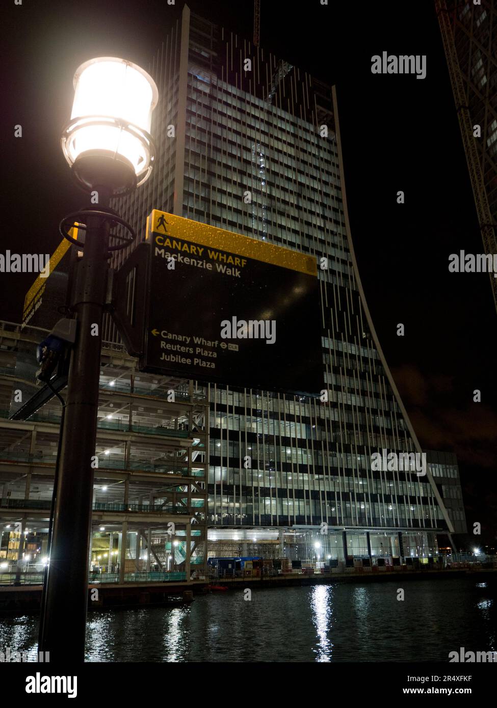 Mackenzie Walk sign with glass building annd river Thames at night ...