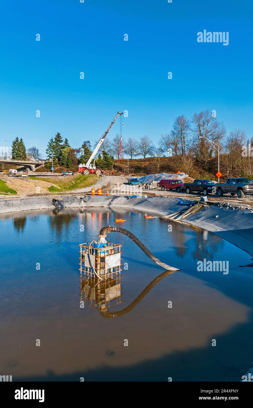 A temporary pond to provide water to a construction site. A crane is ...