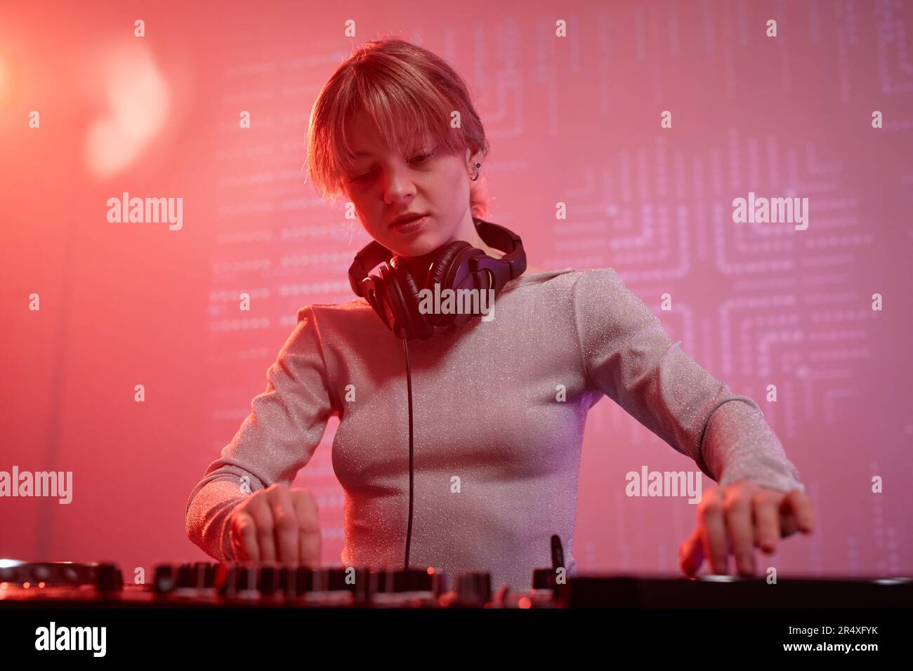 Portrait of young woman as female DJ making music tracks at disco party ...