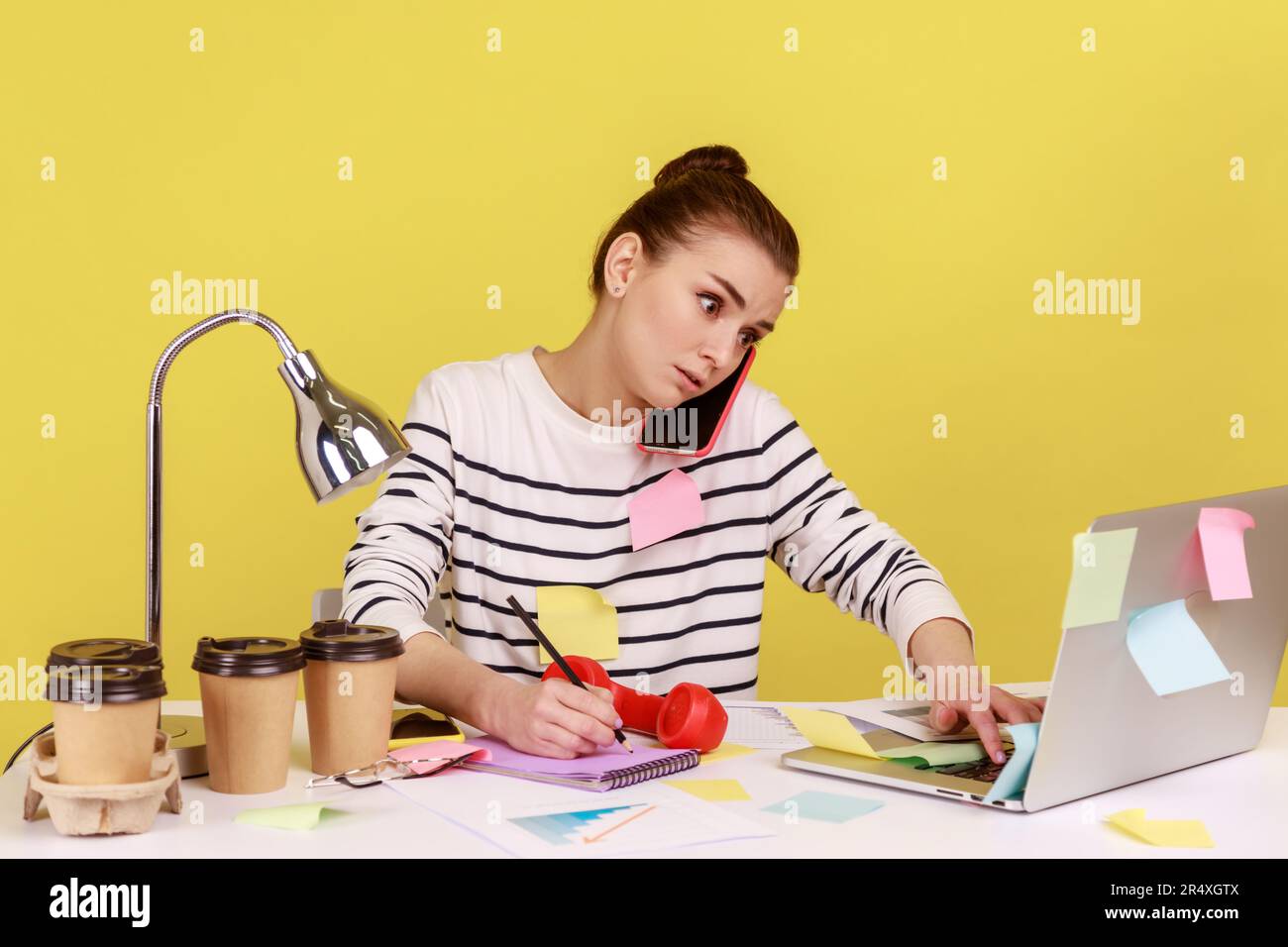 Concentrated secretary in striped shirt receiving calls on phone and ...