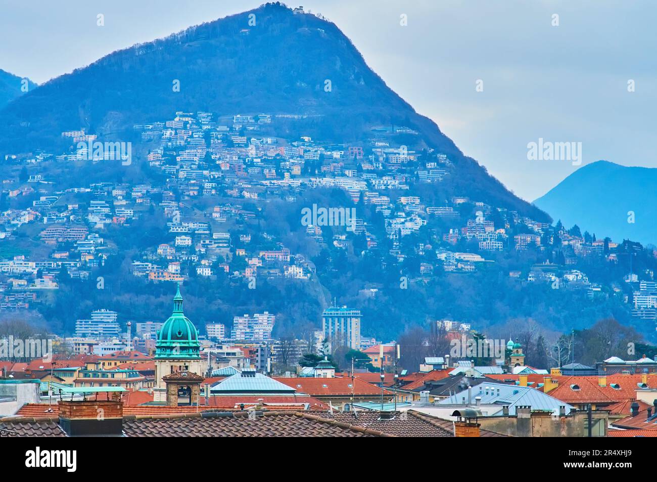 The lush forests and small houses on the slope of Monte Bre in dimmed ...