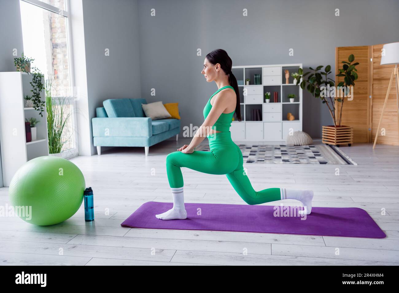 Full body profile portrait of concentrated energetic lady doing lunges stretching legs fitness ...
