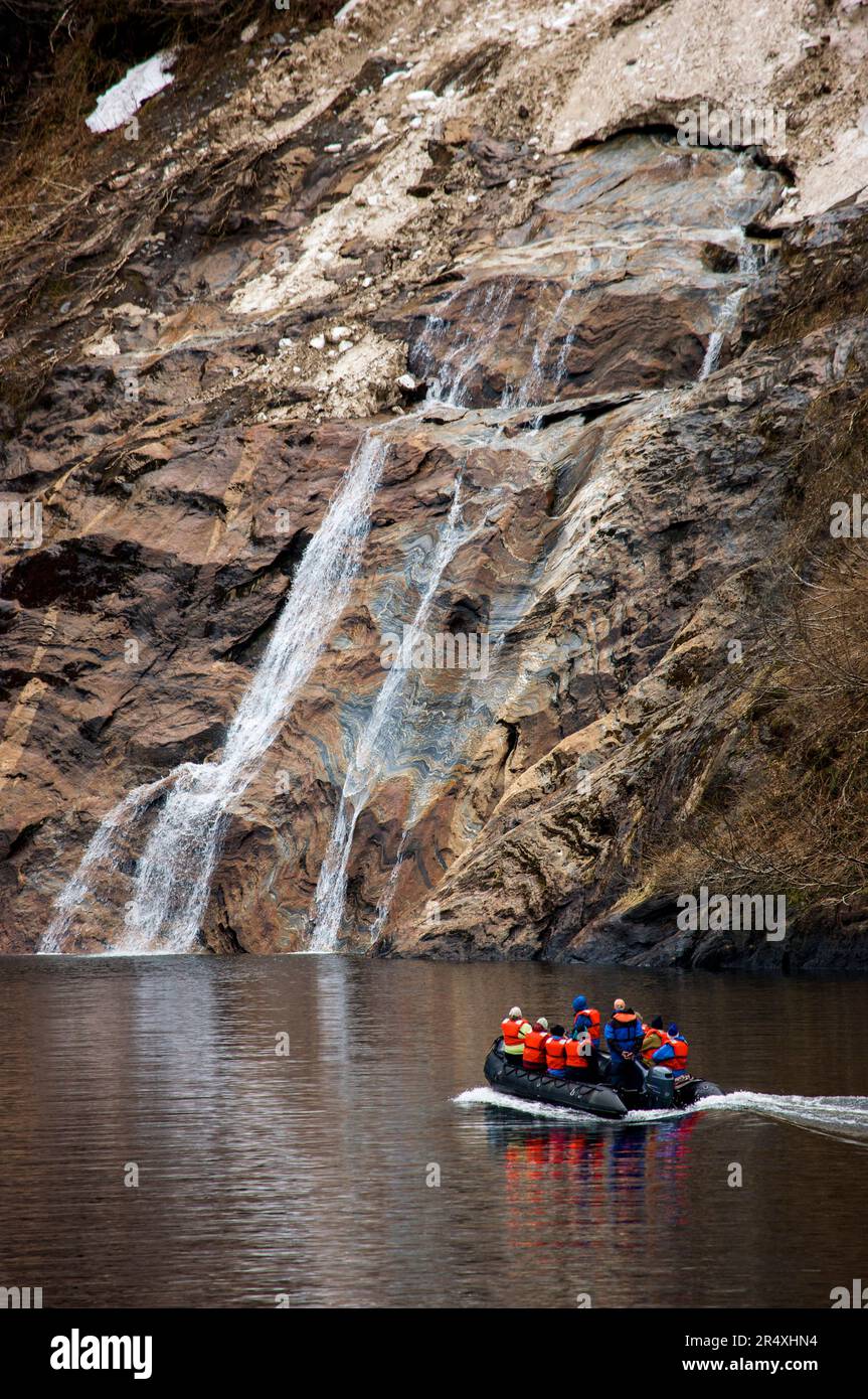 Ecotourists approach a waterfall in an inflatable raft in Rudyard Bay ...