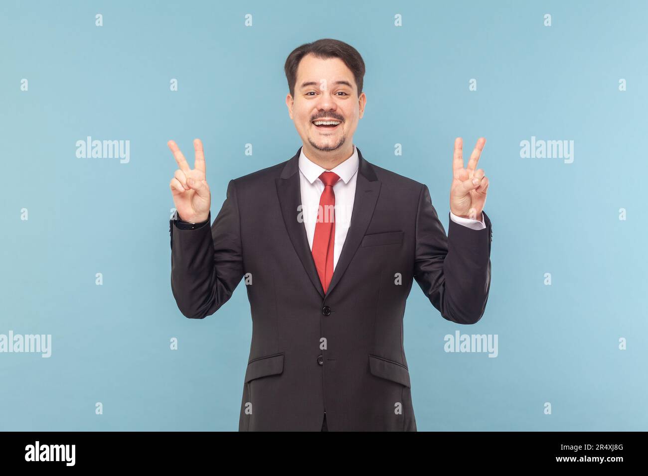 Excited happy positive man with mustache standing and showing v sign ...