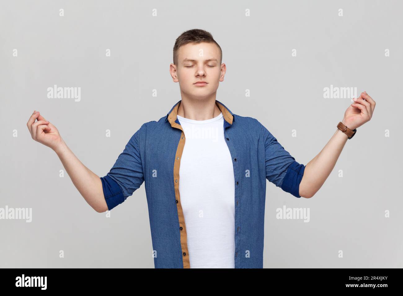 Portrait of calm meditative handsome teenager boy wearing blue shirt ...