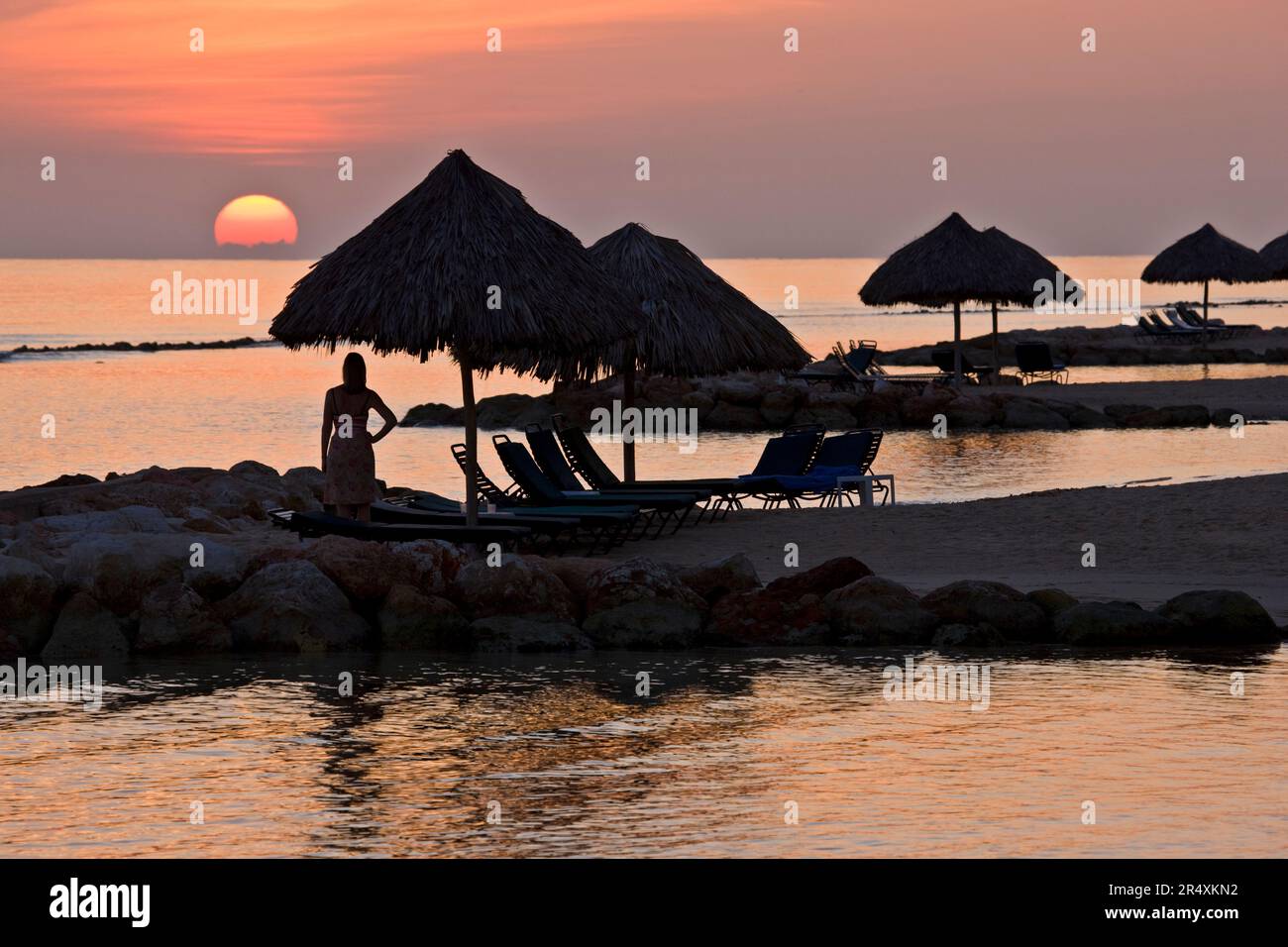 Tourist stands watching the sunset from a Jamaican resort; Montego Bay ...