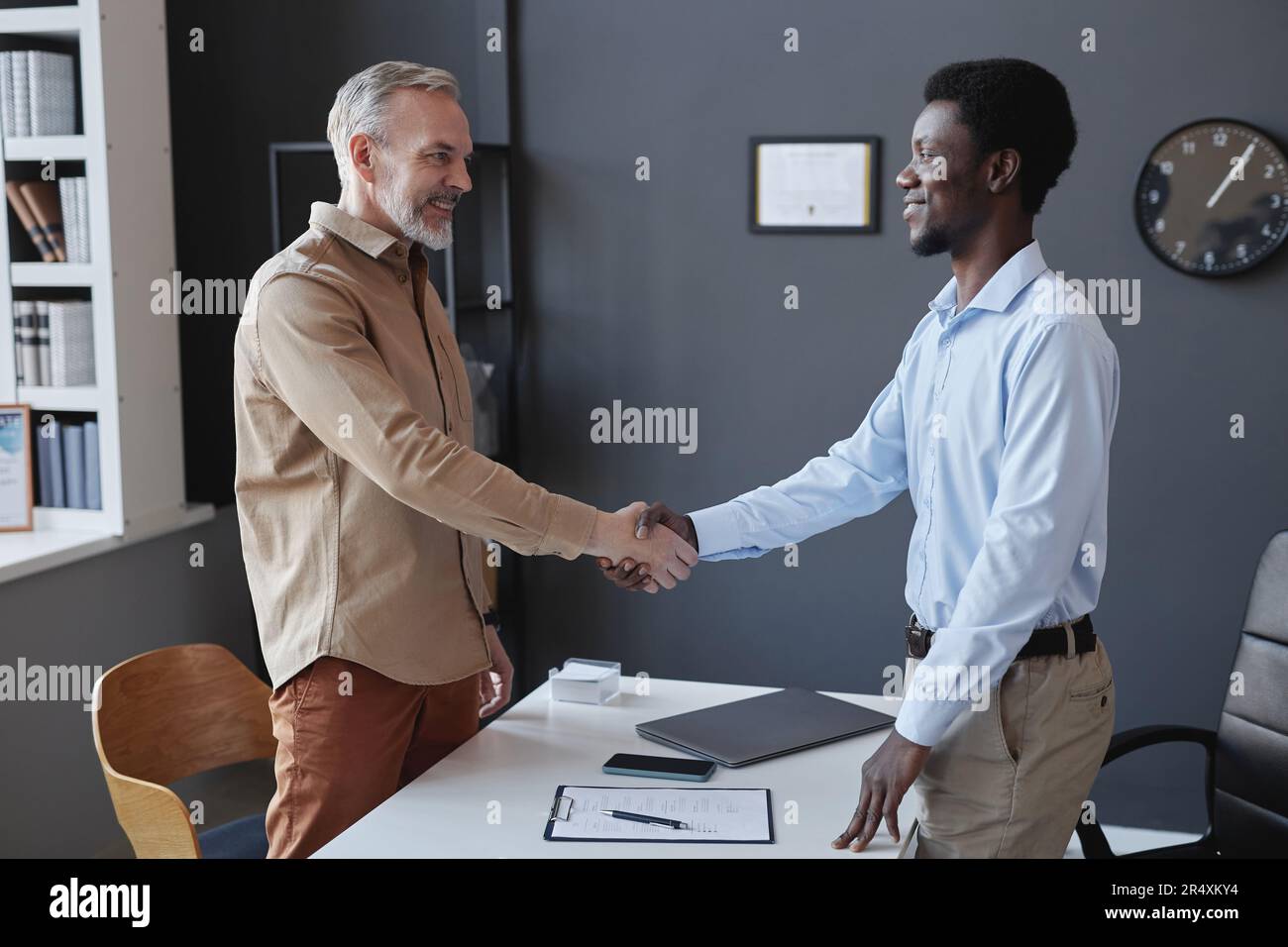 Side view portrait of smiling senior candidate shaking hands with ...