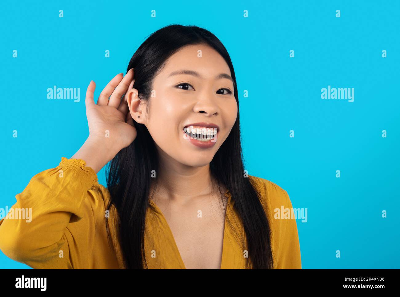 Beautiful african woman holding hand near ear, blue background Stock ...