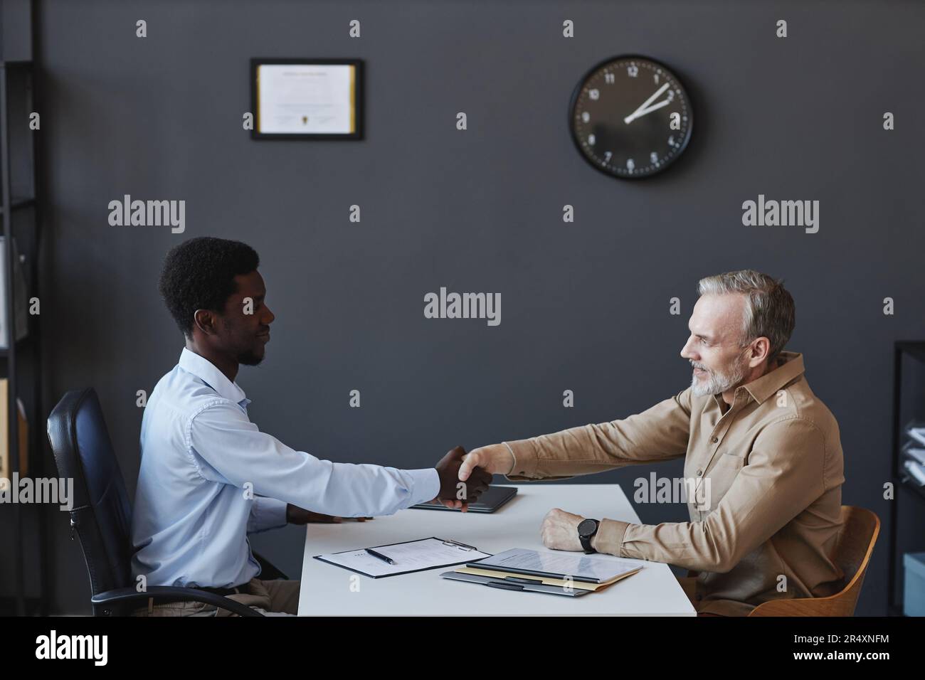 Side view portrait of HR recruiter shaking hands with smiling senior ...