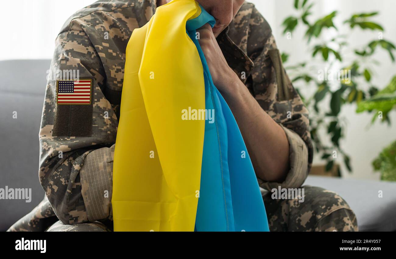 American Flag on Soldiers arm and flag of the Ukraine at background. US ...