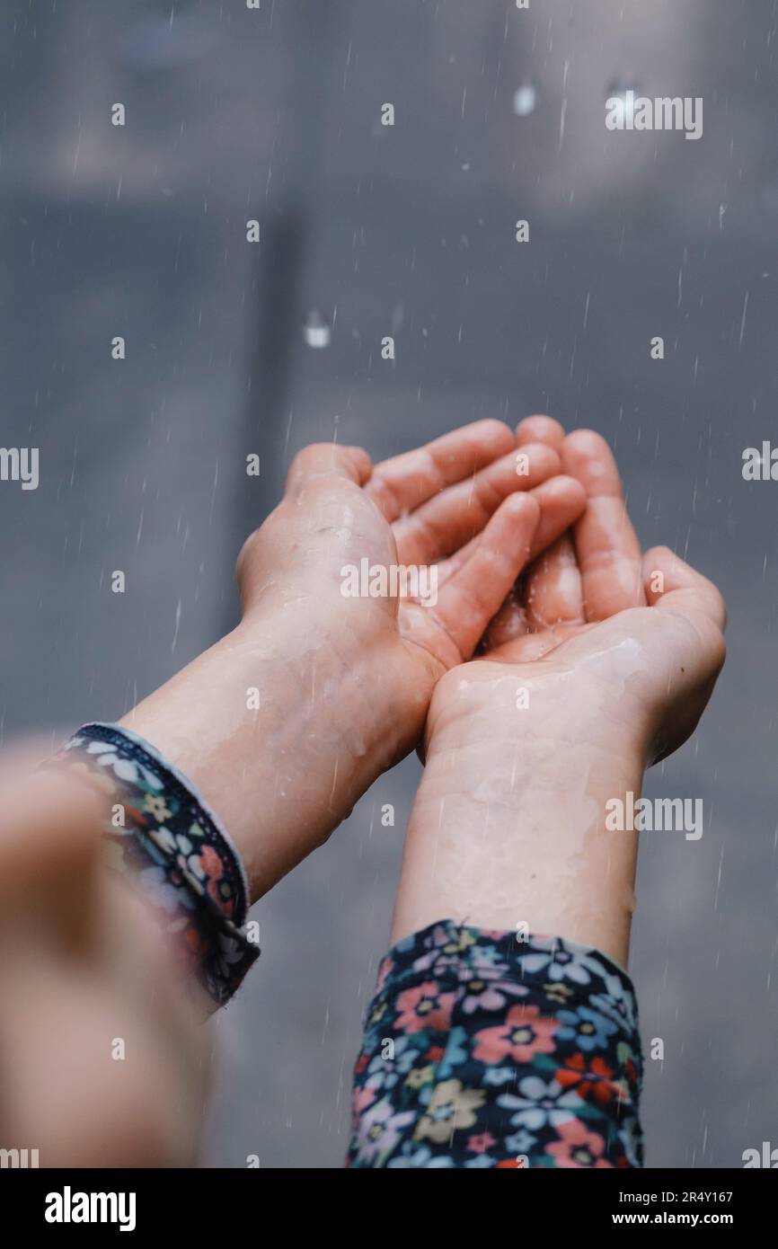 kids hands catching raindrops, weather concept. Closeup of rain falling ...