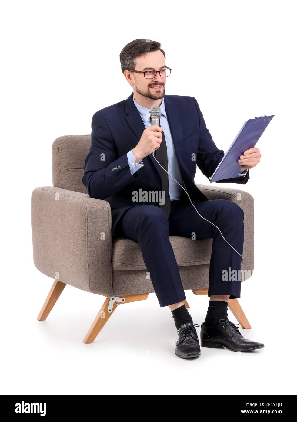 Male journalist with microphone and clipboard in armchair on white ...