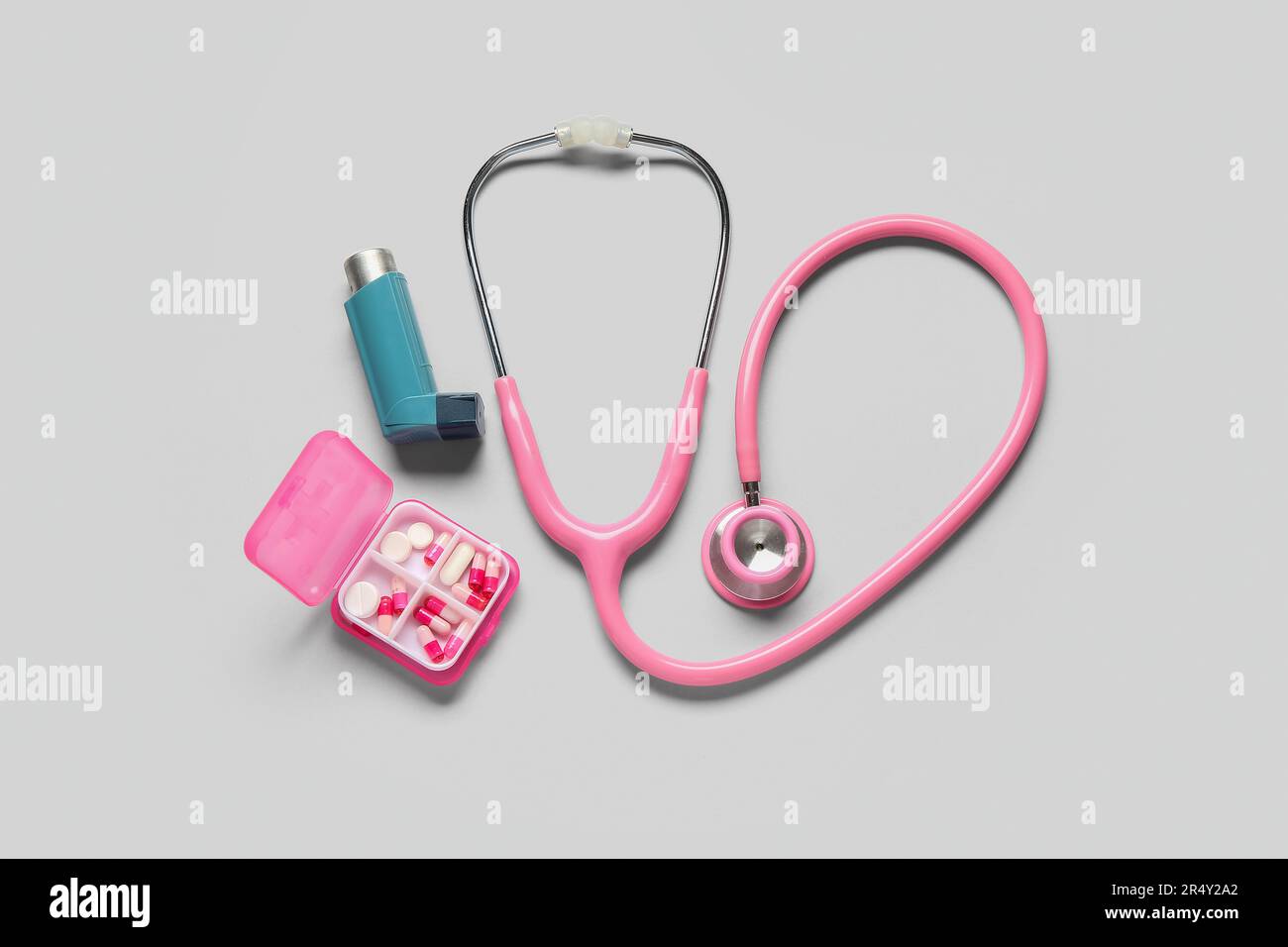 Composition with asthma inhaler, stethoscope and box of pills on grey ...