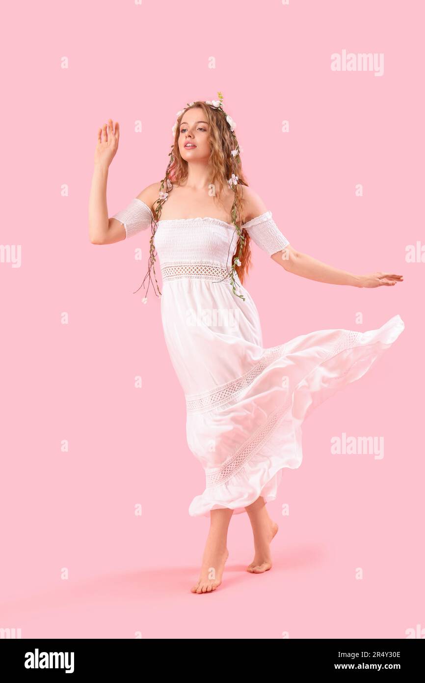 Beautiful young woman with flowers in her hair on pink background ...