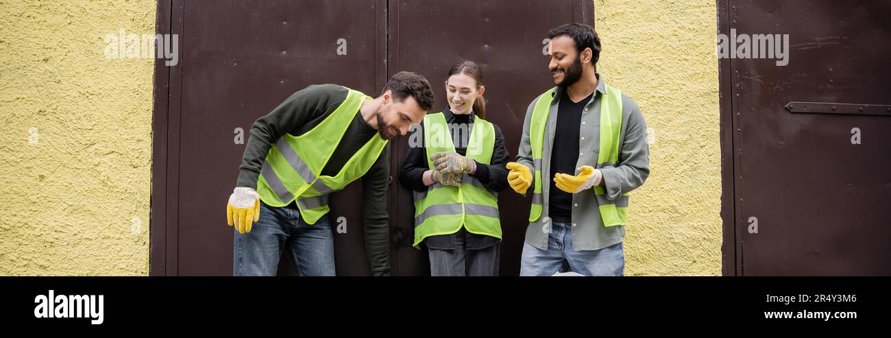 Positive multiethnic workers in high visibility vests and gloves ...