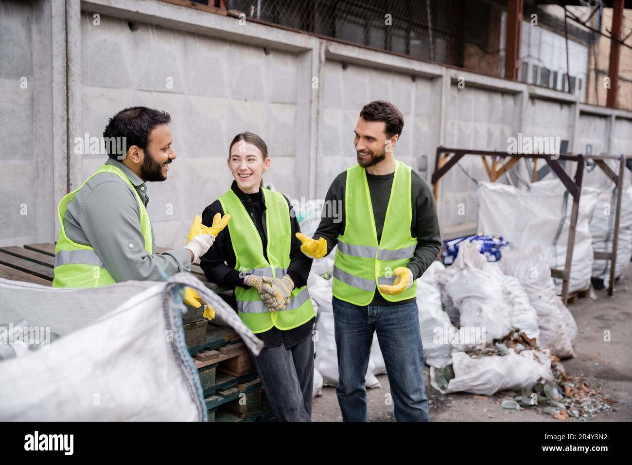 Positive worker in high visibility vest and gloves talking to ...