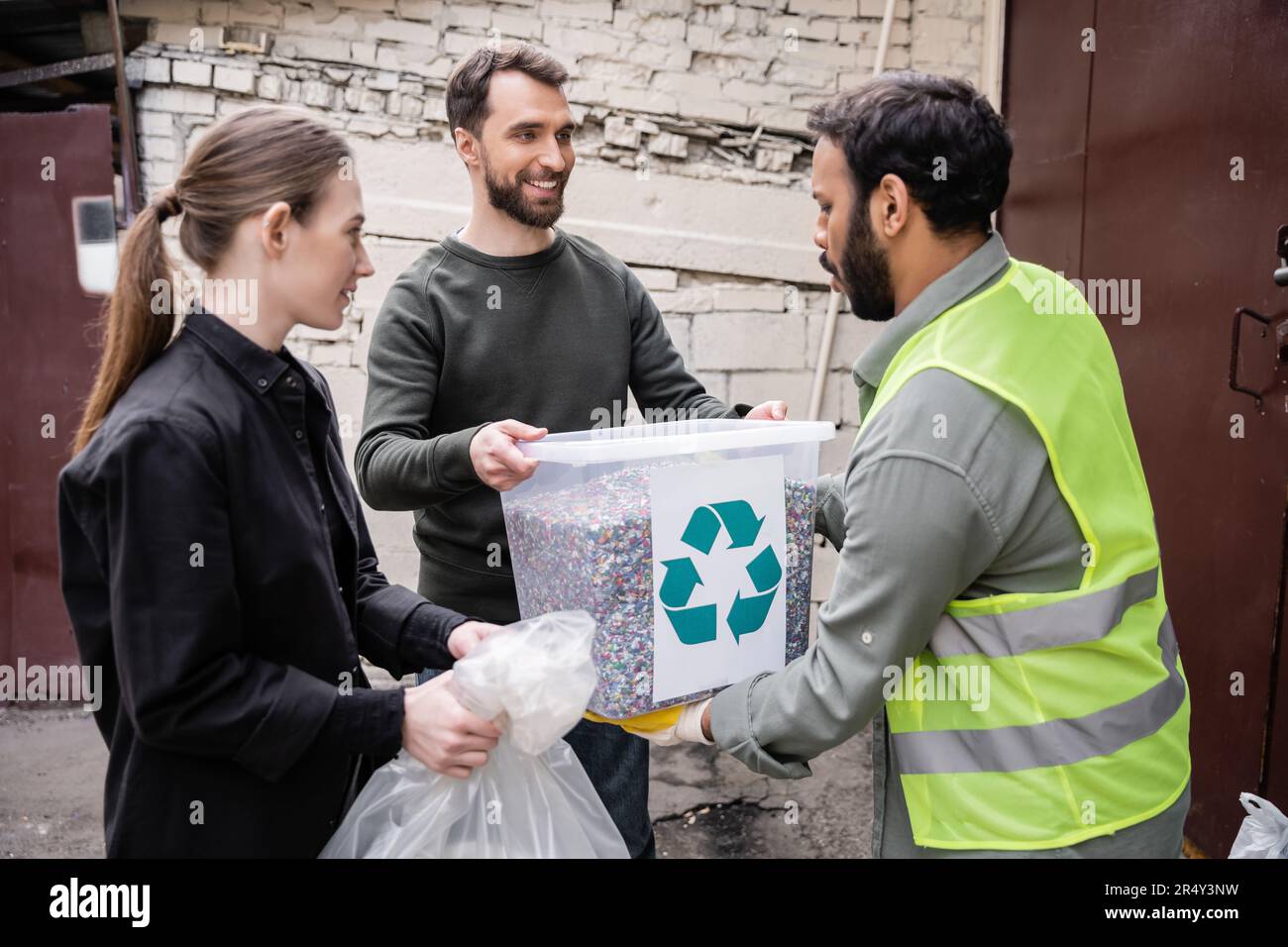 Smiling volunteers giving trash to indian worker in high visibility ...
