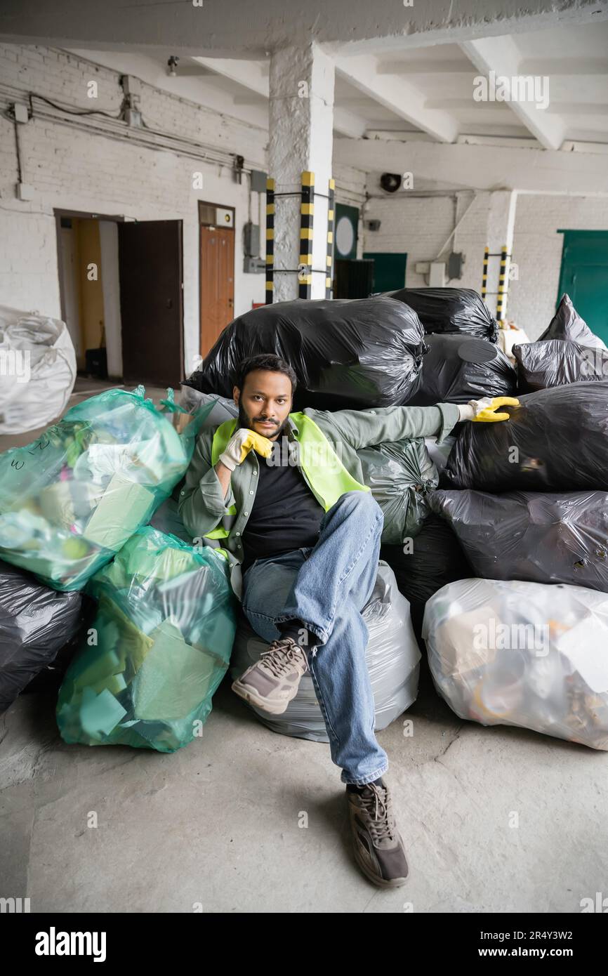 Confident indian worker in high visibility vest and gloves looking at ...