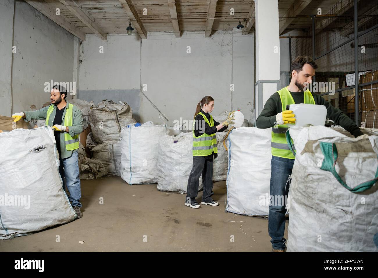 Multiethnic workers in high visibility vests and gloves separating ...
