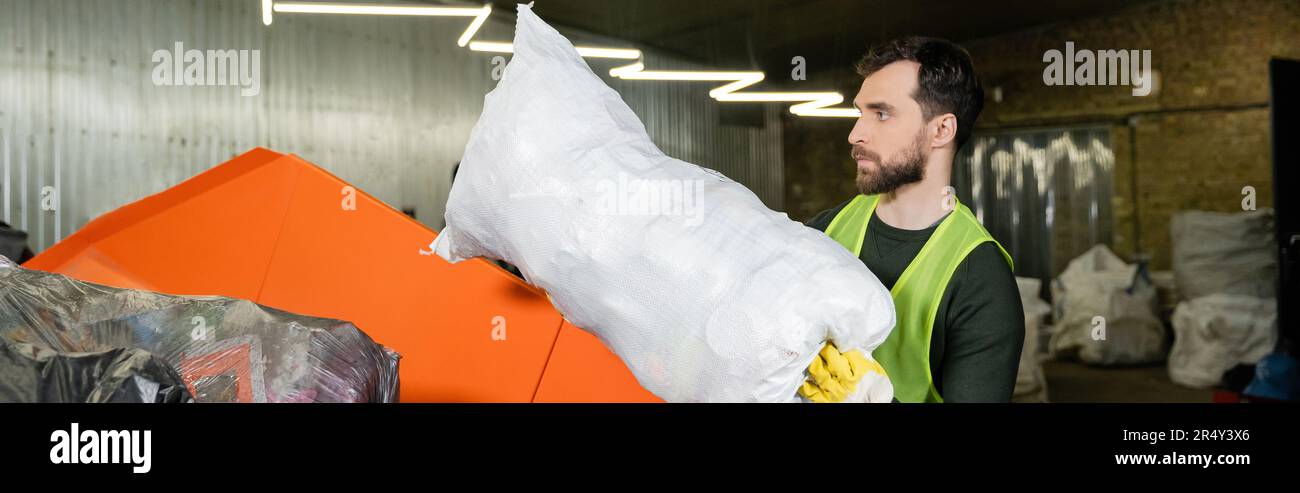 Side view of bearded man in protective vest and glove putting sack with ...