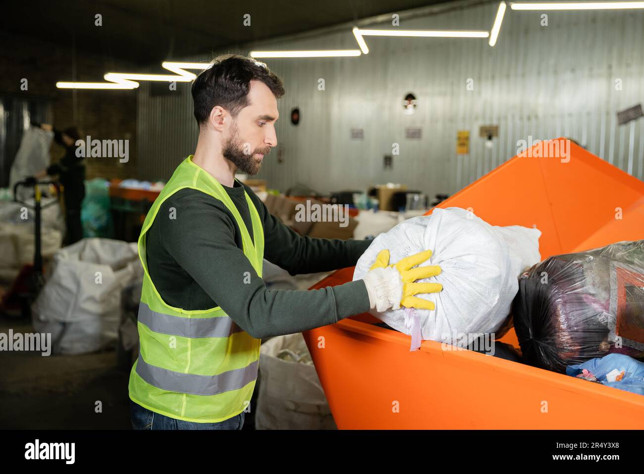 Side view of sorter in glove and protective vest putting sack in ...