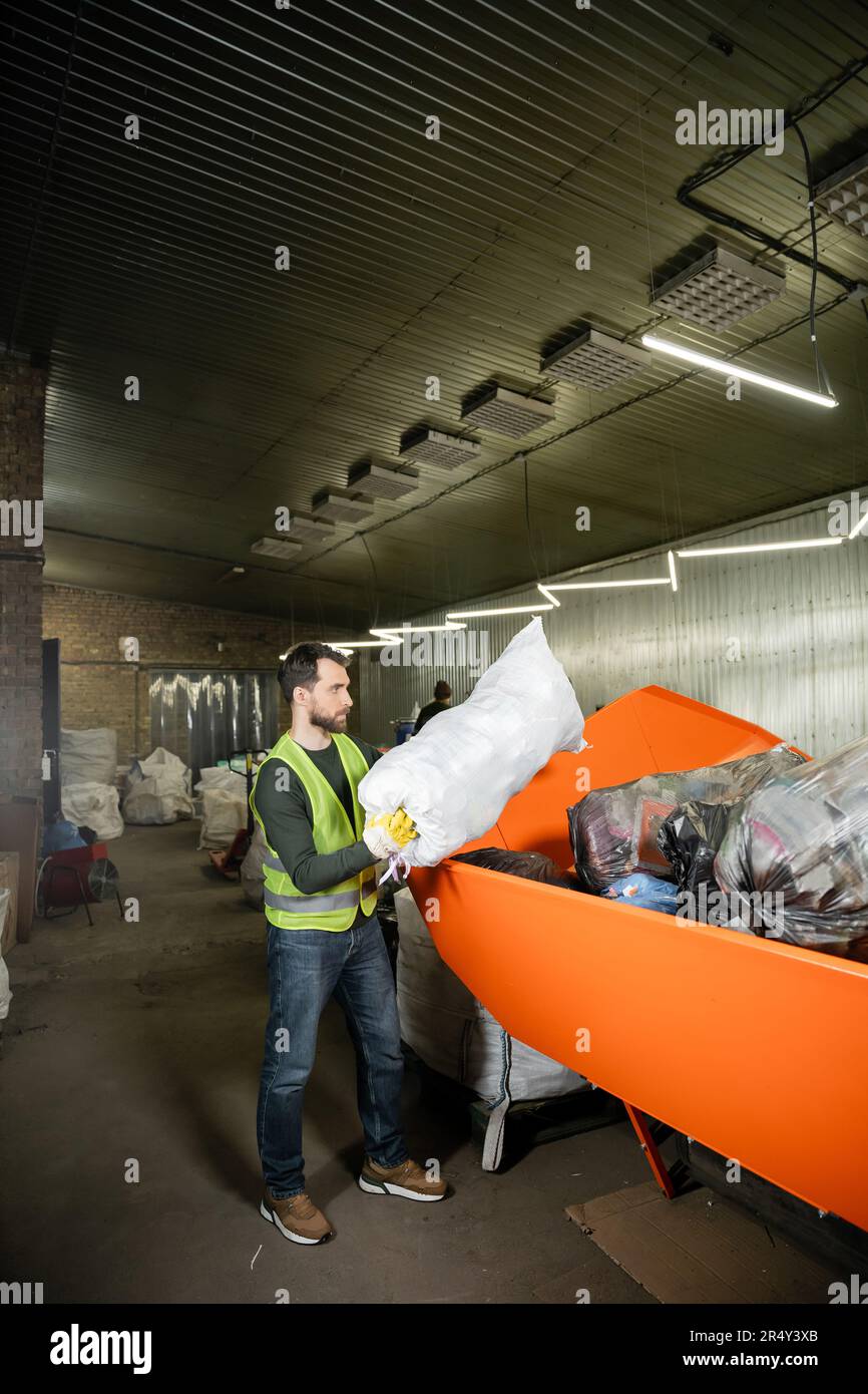 Side view of bearded male worker in glove and fluorescent vest putting ...