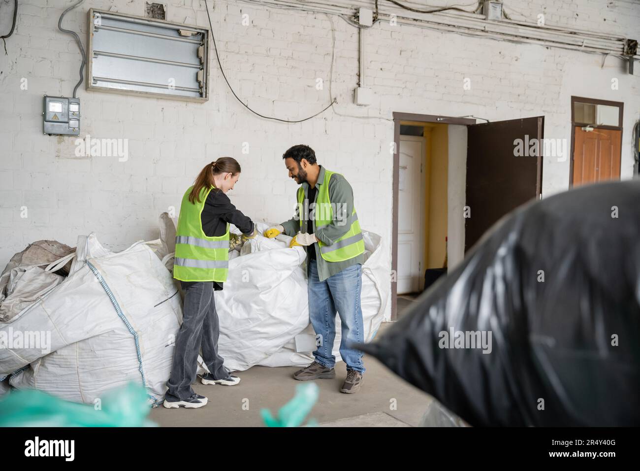 Side view of young worker in high visibility vest and gloves standing ...
