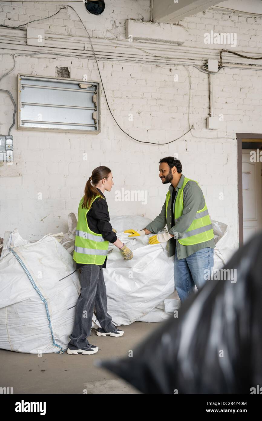 Side view of indian worker in protective vest and gloves standing near ...