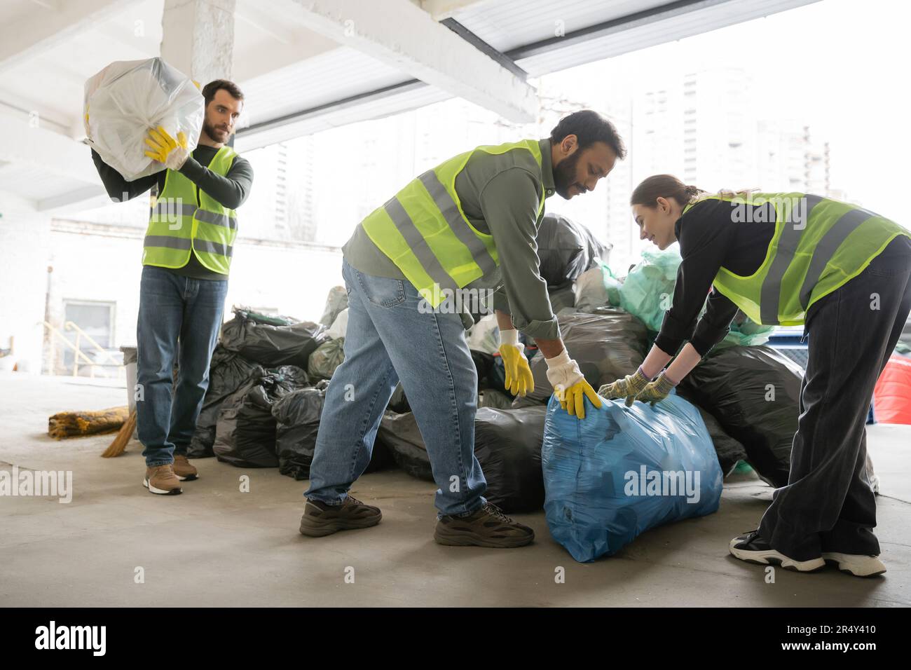 Smiling female worker in high visibility vest and gloves putting ...