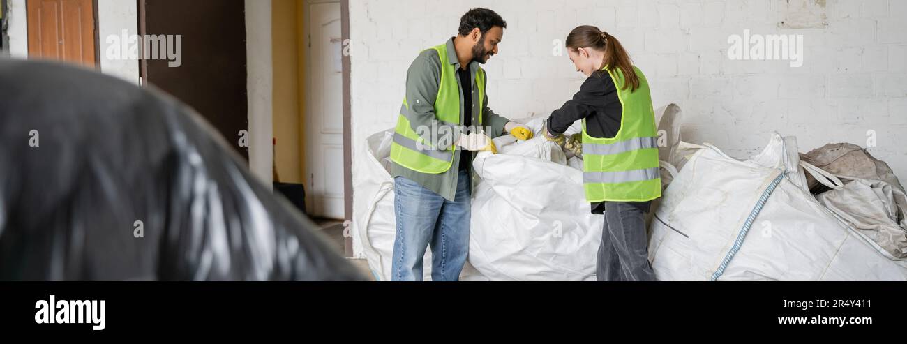 Side view of multiethnic workers in protective vests and gloves ...