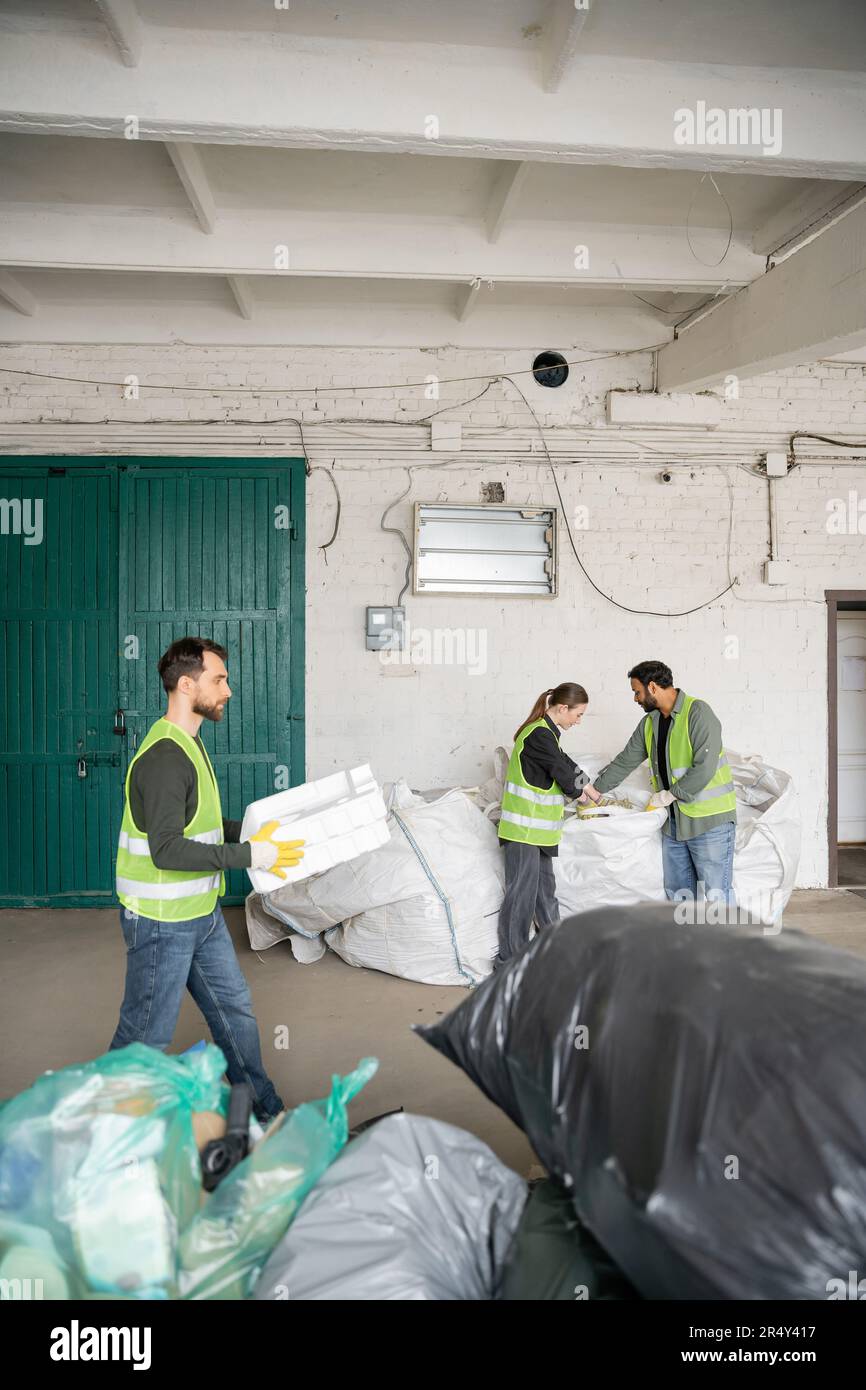 Male worker in high visibility vest and gloves carrying foam plastic ...