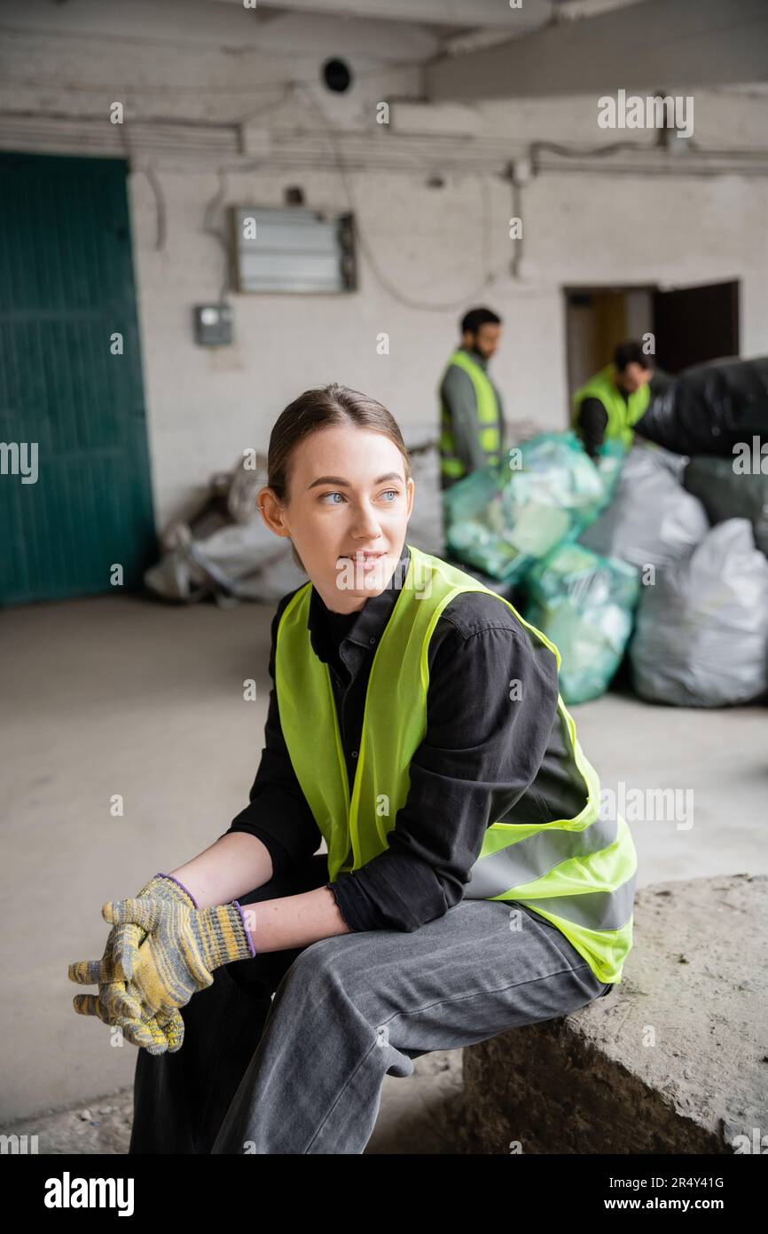 Positive young sorter in high visibility vest and gloves looking away ...