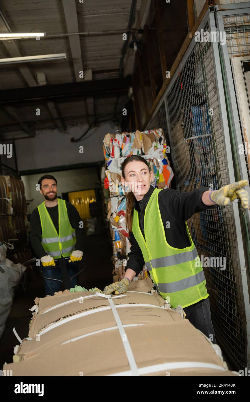 worker in protective vest and gloves pointing with finger away while ...