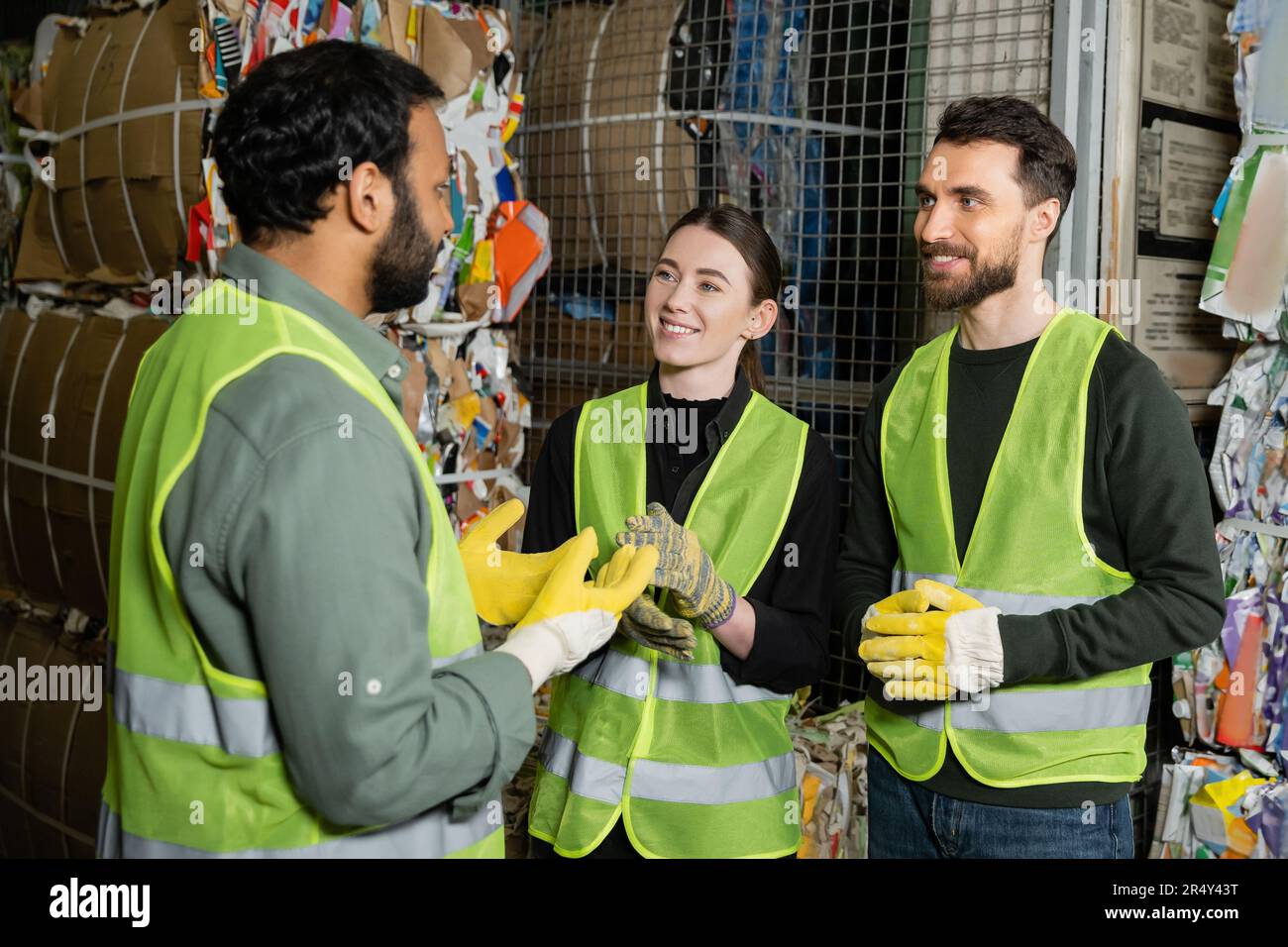 Indian worker in high visibility vest and gloves talking to smiling ...