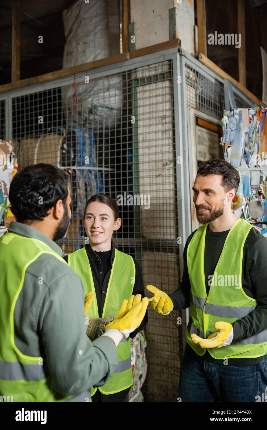 Smiling male worker in safety vest and gloves talking to indian ... Smiling male worker in safety vest and gloves talking to indian ...
