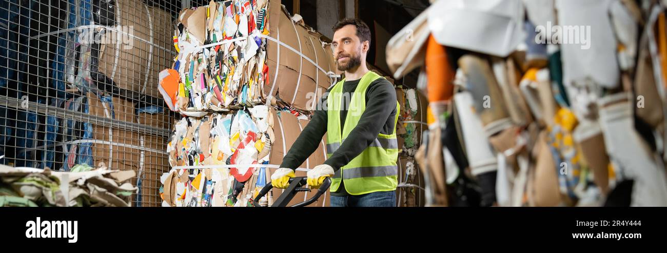 Bearded sorter in high visibility vest and gloves standing near hand ...