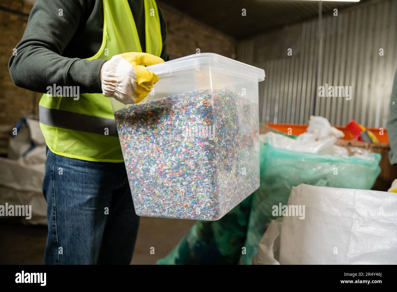 Cropped view of worker in high visibility vest and glove holding ...