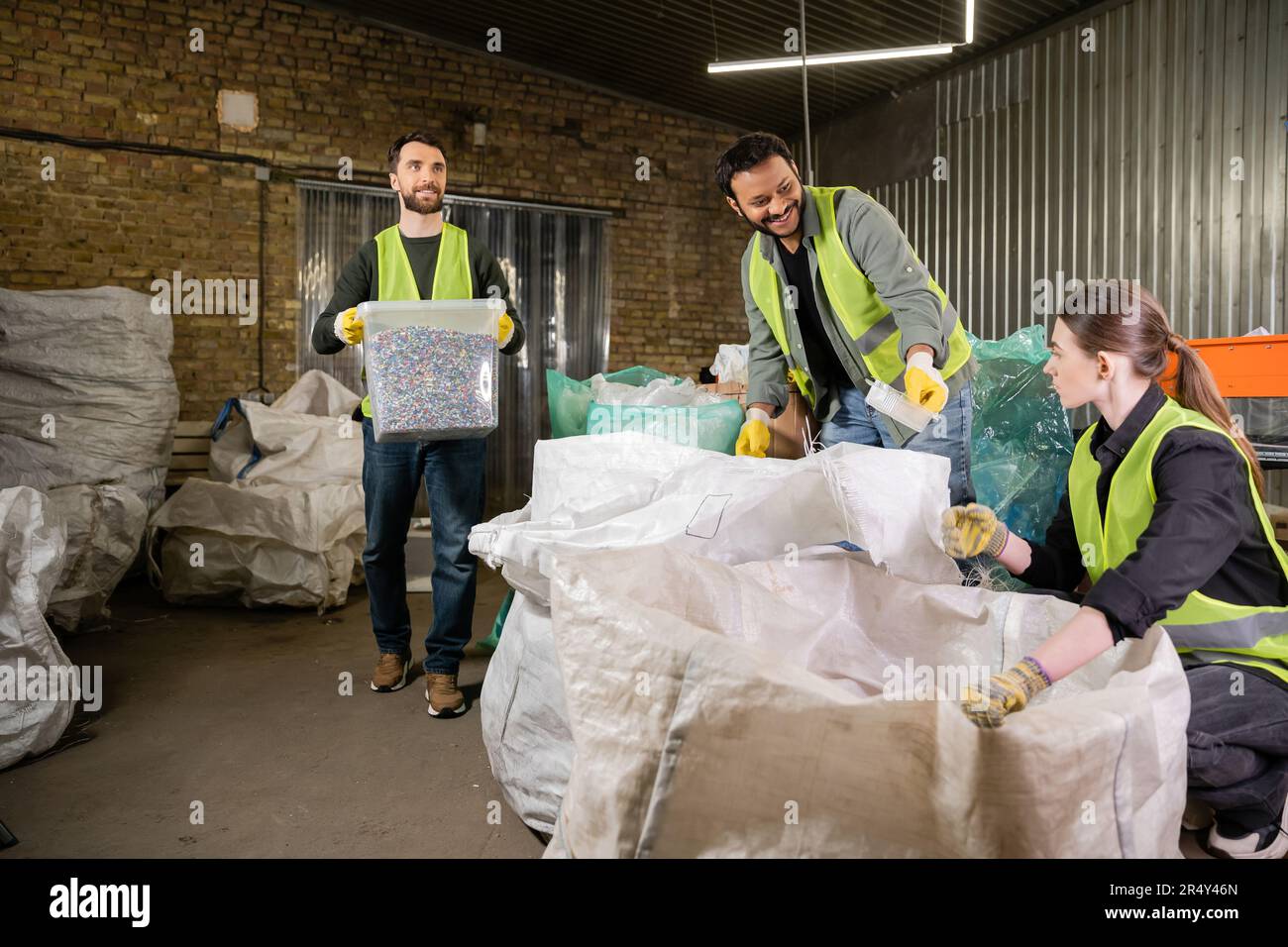 Smiling indian worker in safety vest and gloves giving plastic trash to ...