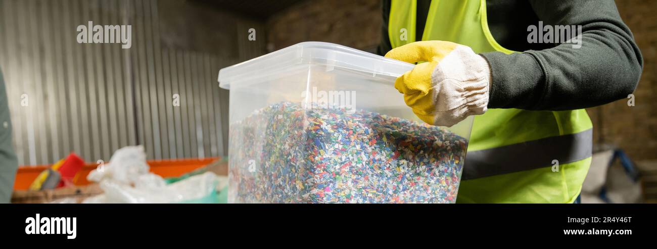 Cropped view of sorter in protective vest and glove holding container ...