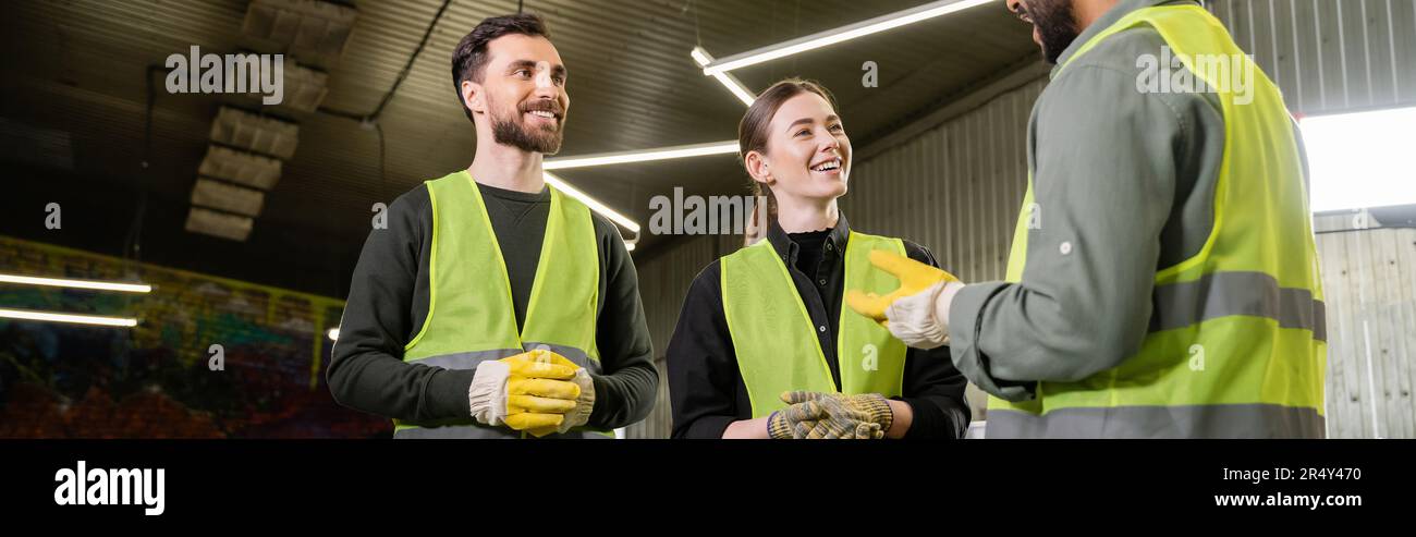 Cheerful workers in protective gloves and high visibility vests looking ...