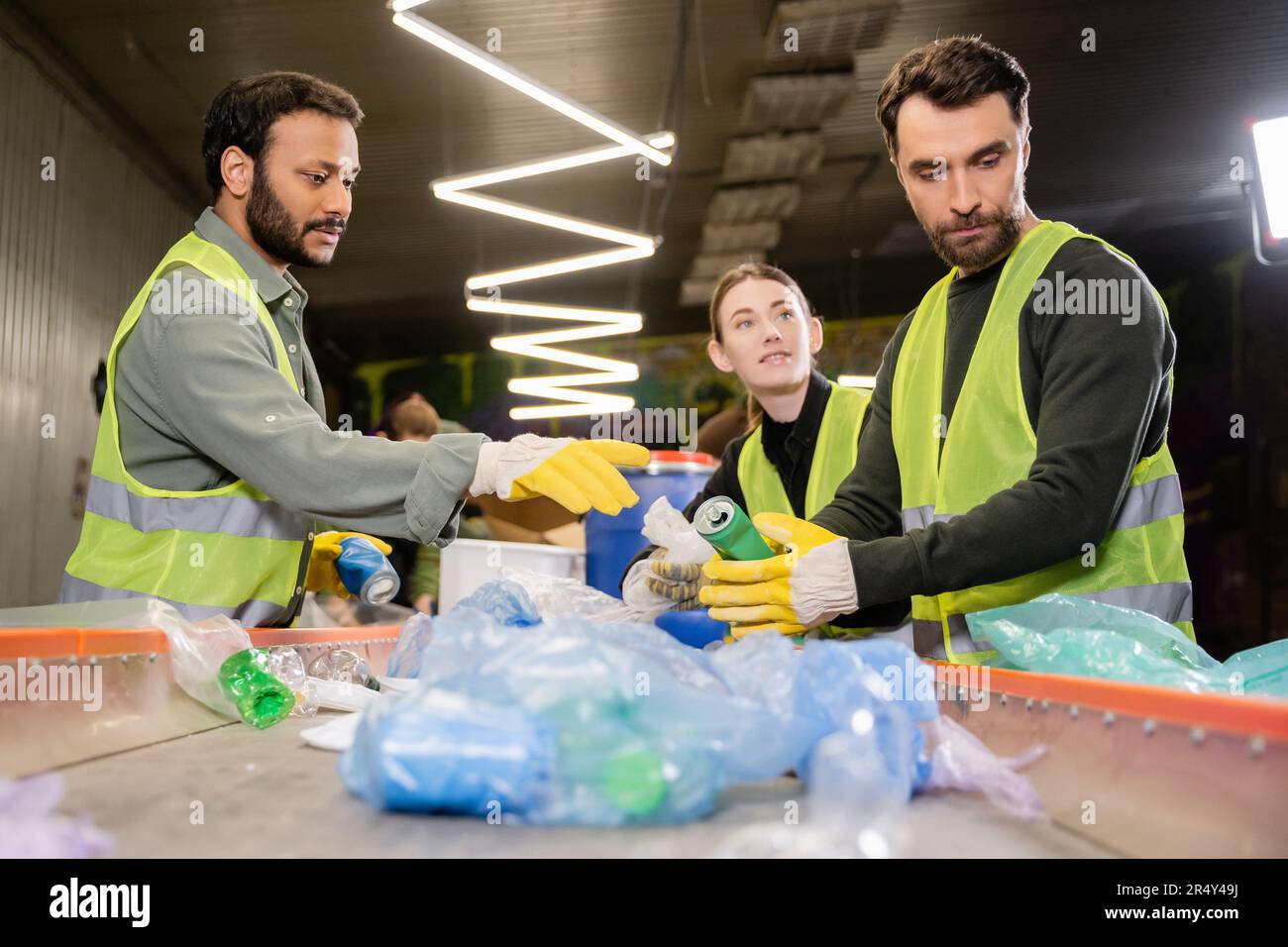 Multiethnic sorters in protective clothes and gloves talking to ...