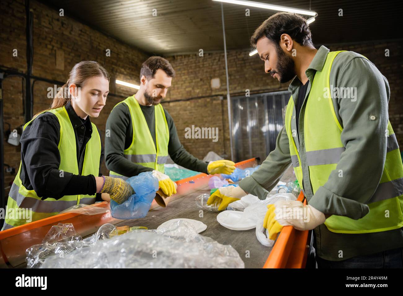 Multiethnic workers in protective vests and gloves taking trash from ...