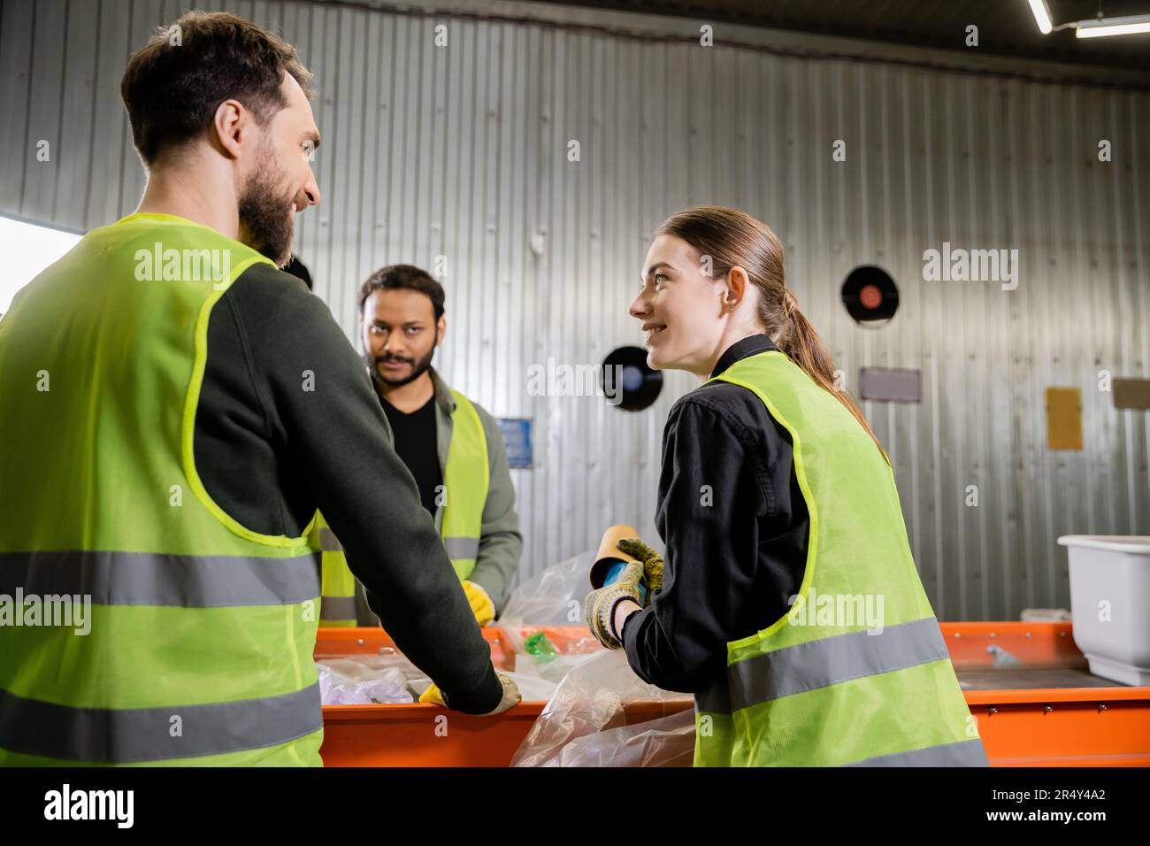 Smiling woman in protective uniform and gloves holding garbage and ...