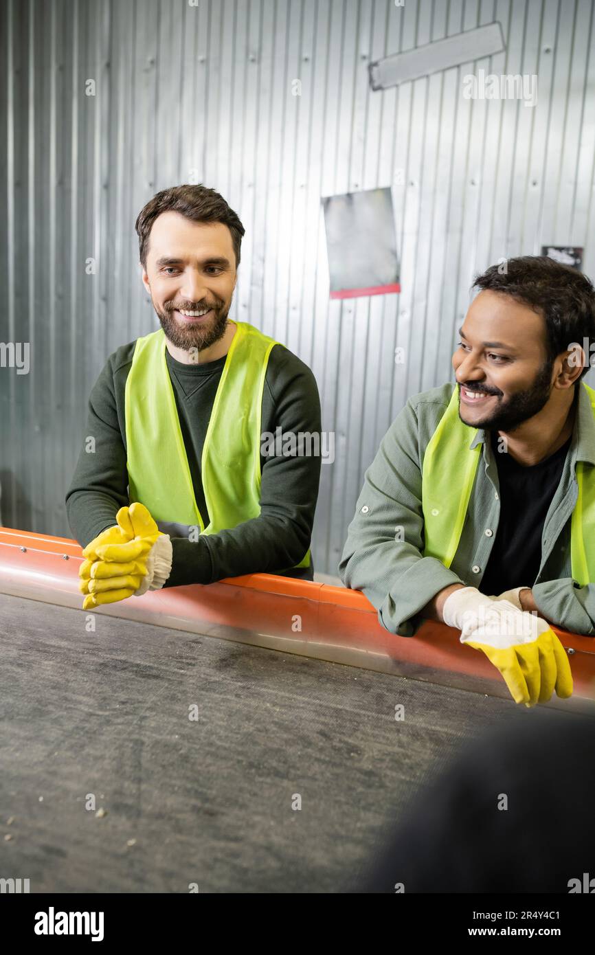 Cheerful multiethnic male sorters in protective clothes and gloves ...
